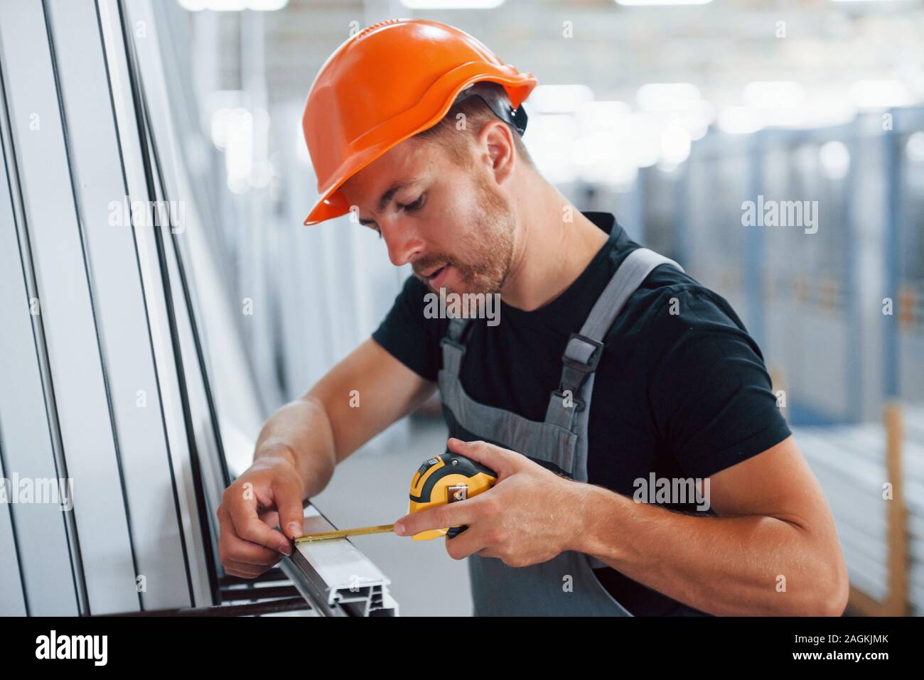 Measuring length of objects. Industrial worker indoors in factory ...