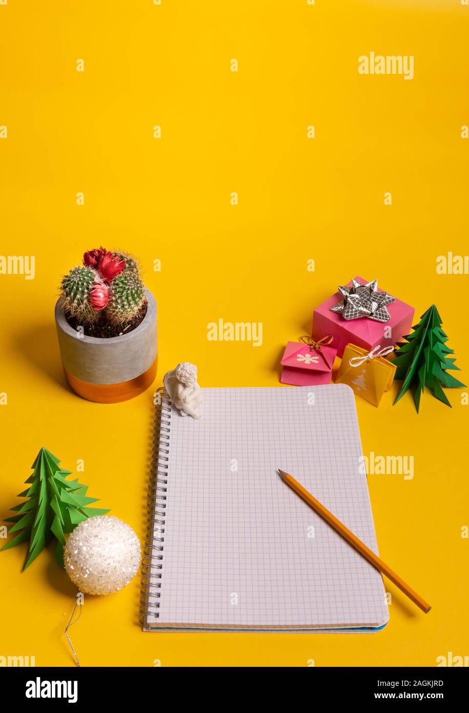 gift box and green origami trees with notepad on yellow desk, table ...