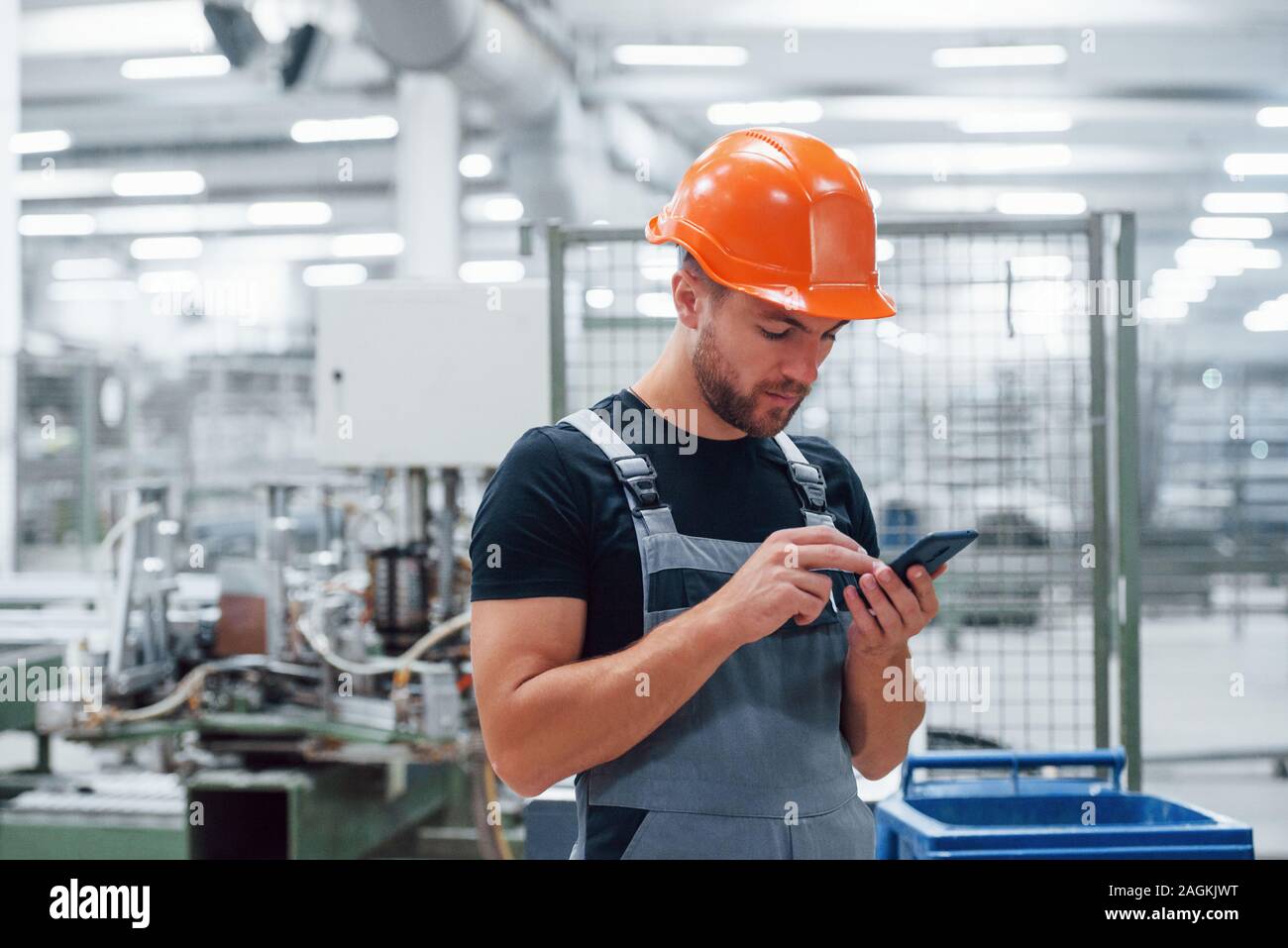 Smartphone in hands. Industrial worker indoors in factory. Young ...