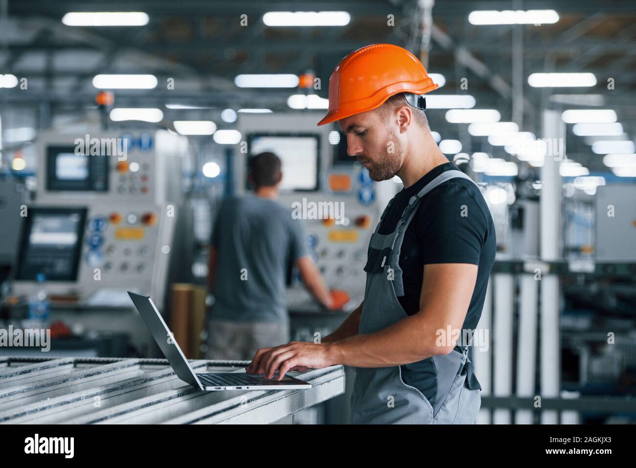 Modern laptop. Typing on keyboard. Industrial worker indoors in factory ...