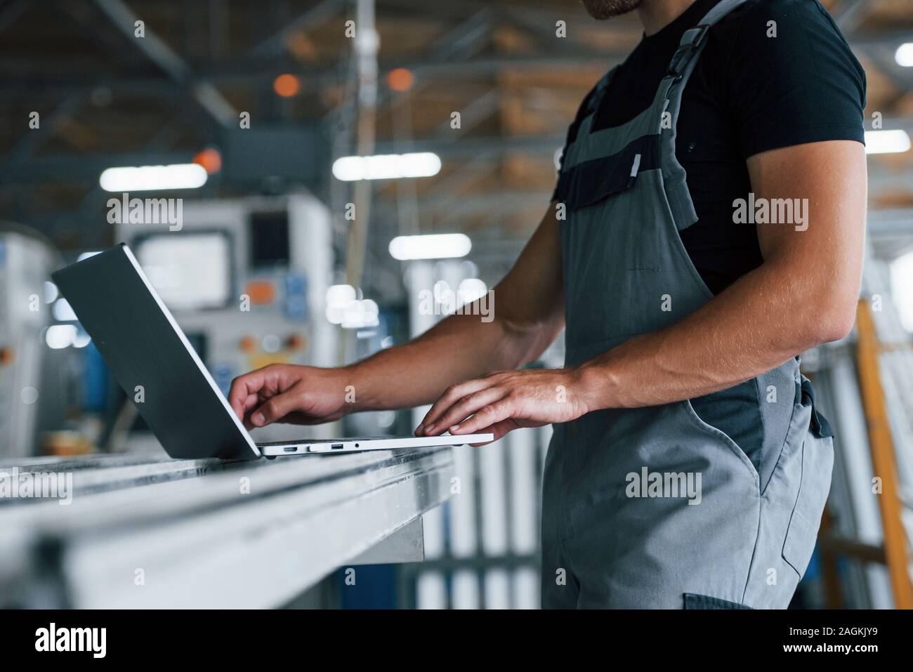Modern laptop. Typing on keyboard. Industrial worker indoors in factory ...