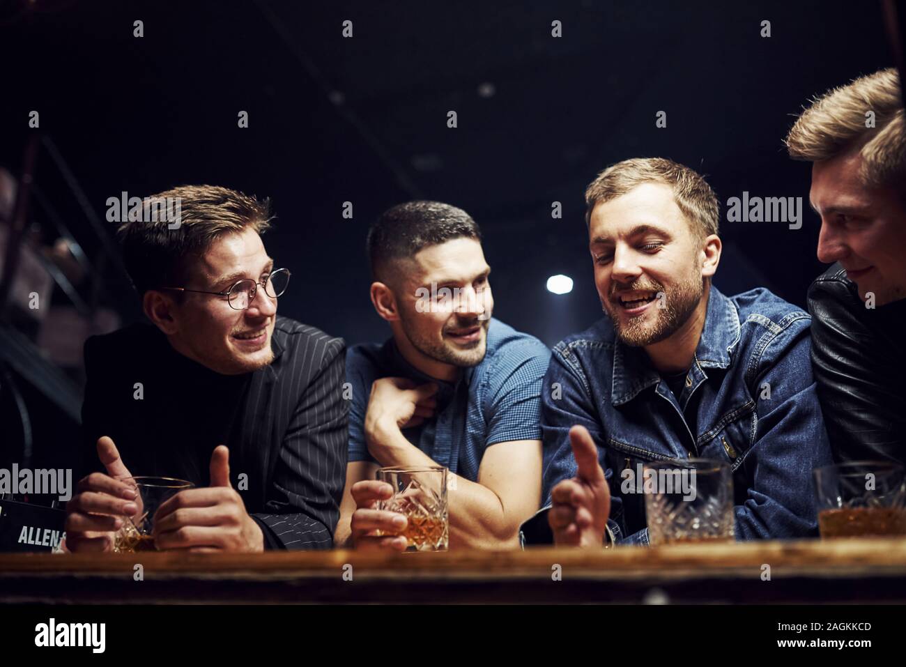 Front view. Friends resting in the pub with alcohol in hands. Having ...