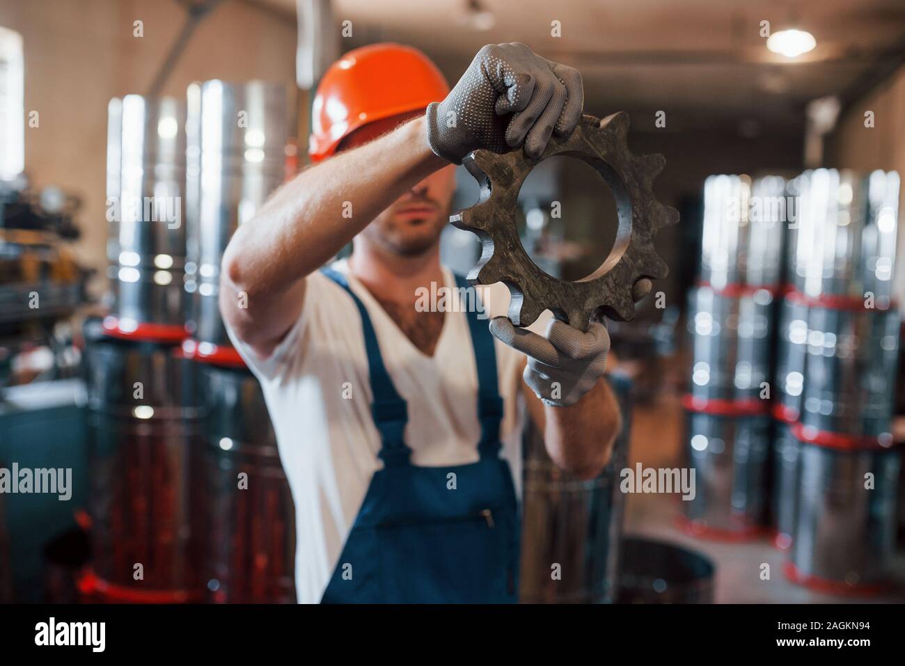 Mechanical gear. Man in uniform works on the production. Industrial ...
