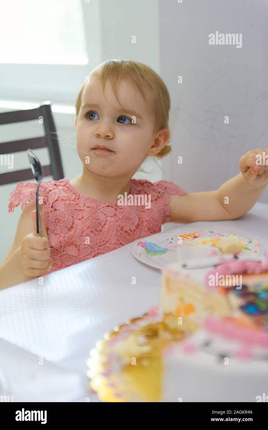Baby girl 1 year old eating birthday cake in room. Birthday party ...