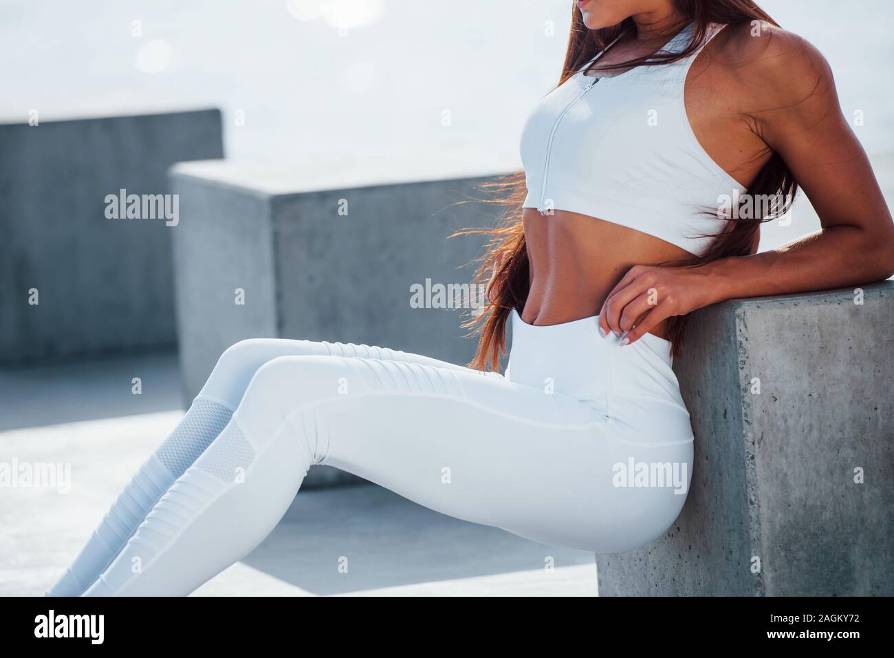 Nice body. Fitness woman having a rest near the lake at daytime ...