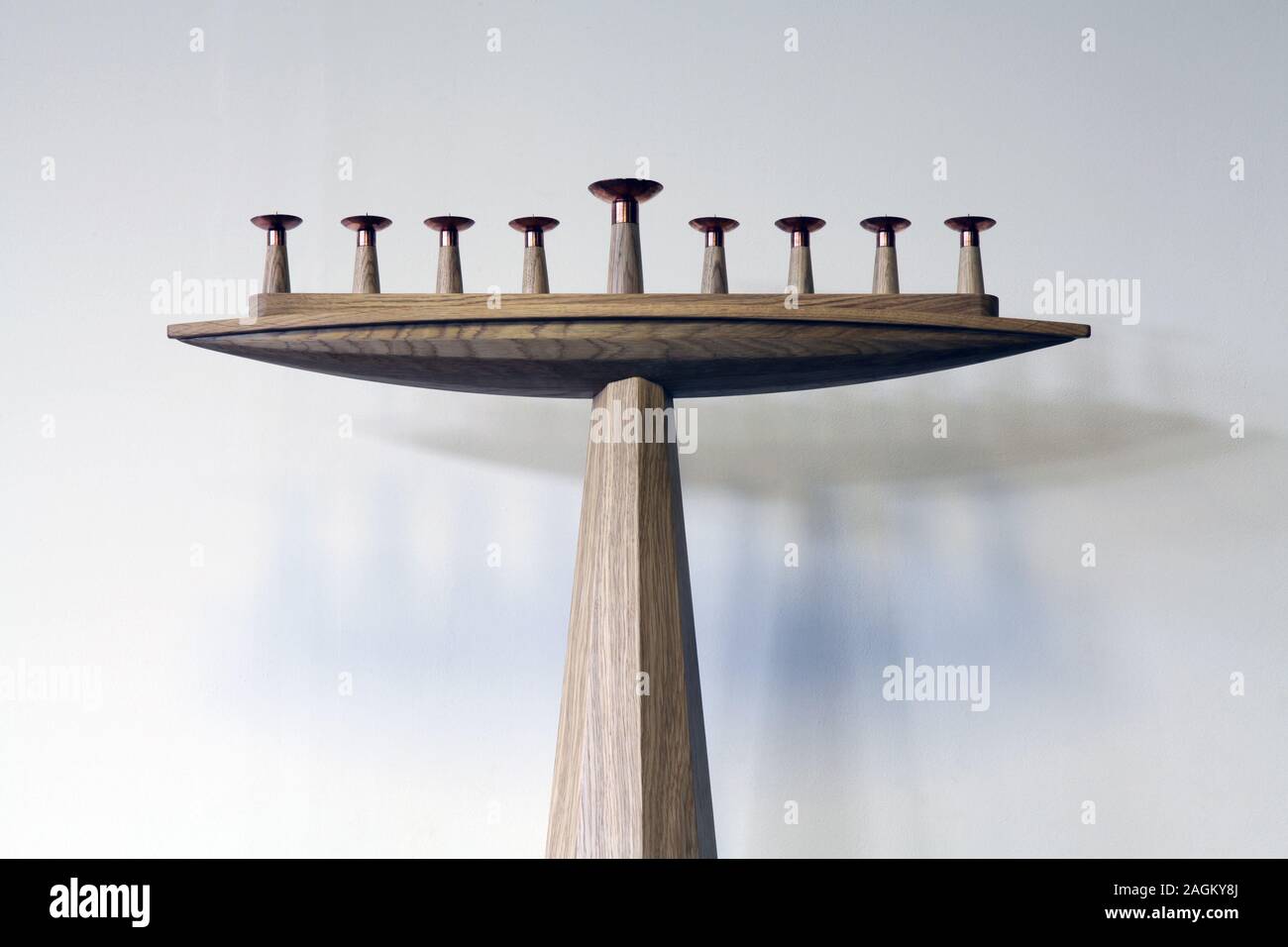A Jewish wooden Menorah standing against a white wall in a Synagogue ...