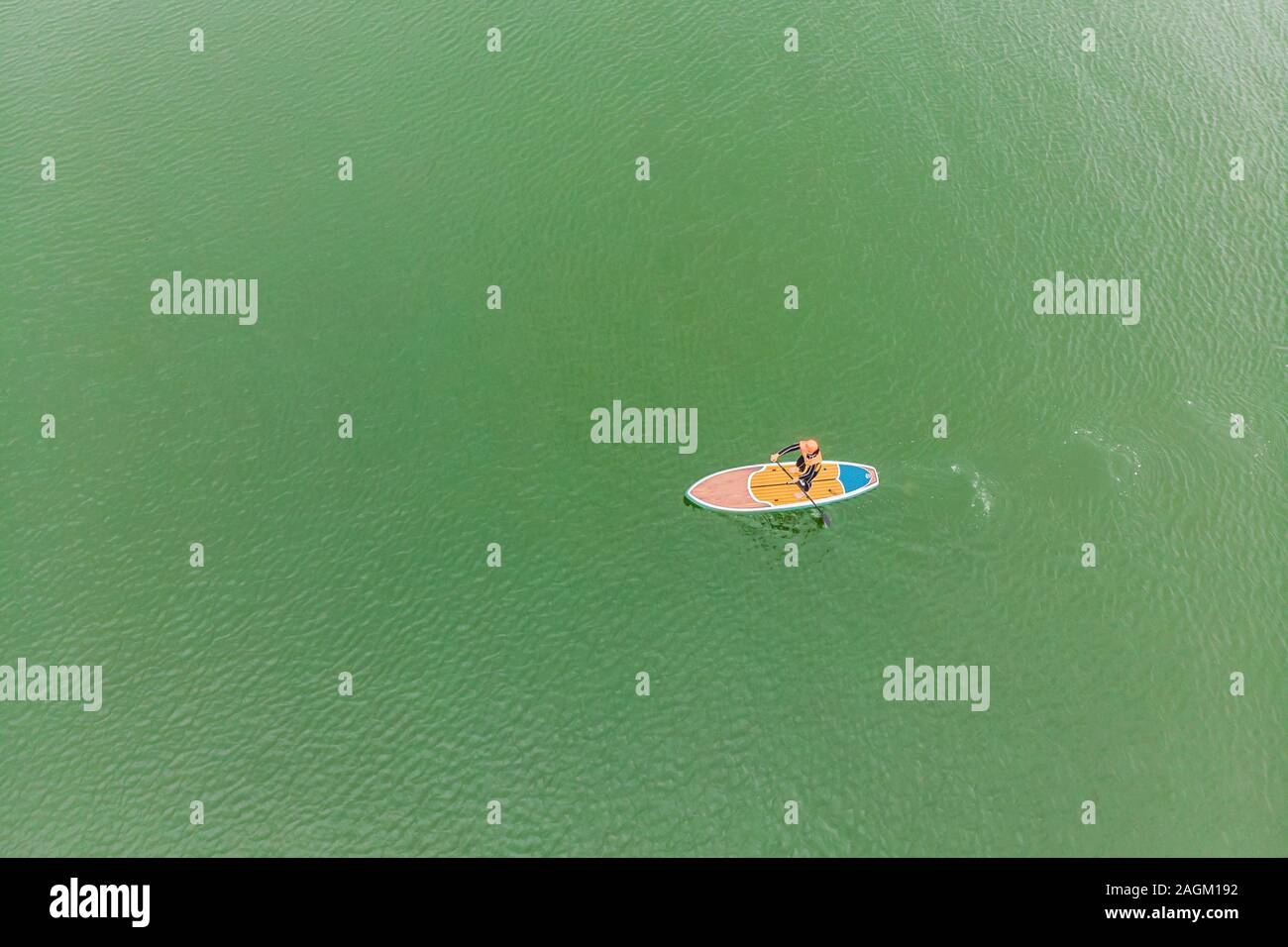 Strong men floating on a SUP boards in a beautiful bay on a sunny day ...