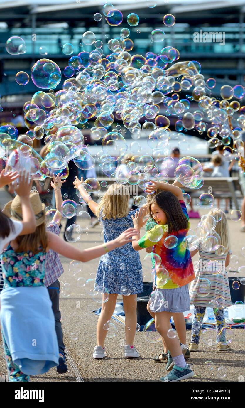 London, England, UK. Children playing with bubbles made by a man making ...