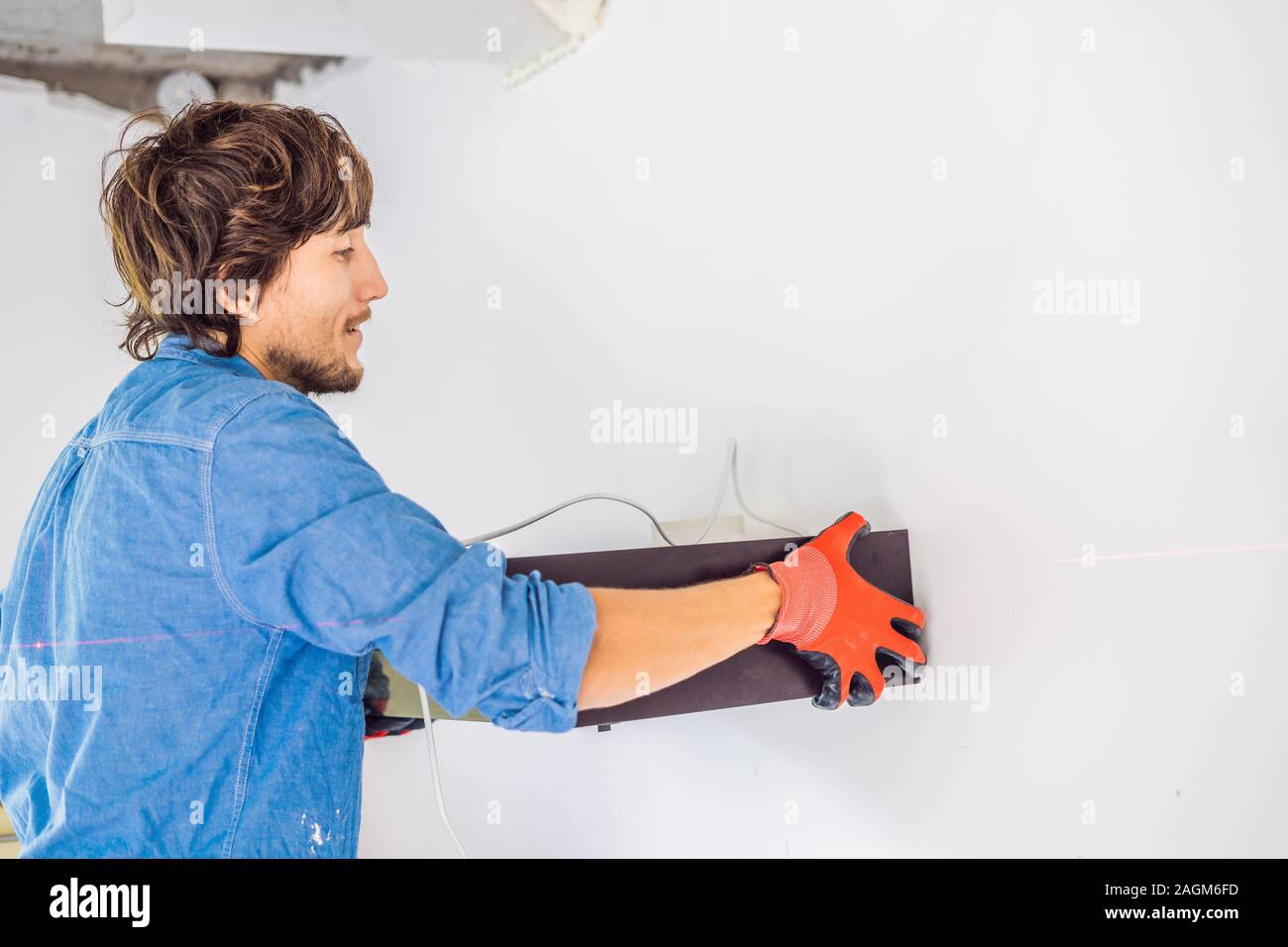 A man is installing an electrical device on a wall in a new apartment ...