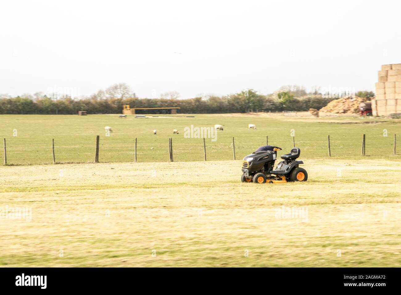 A small ride-on grass cutter sits in an open field Stock Photo - Alamy