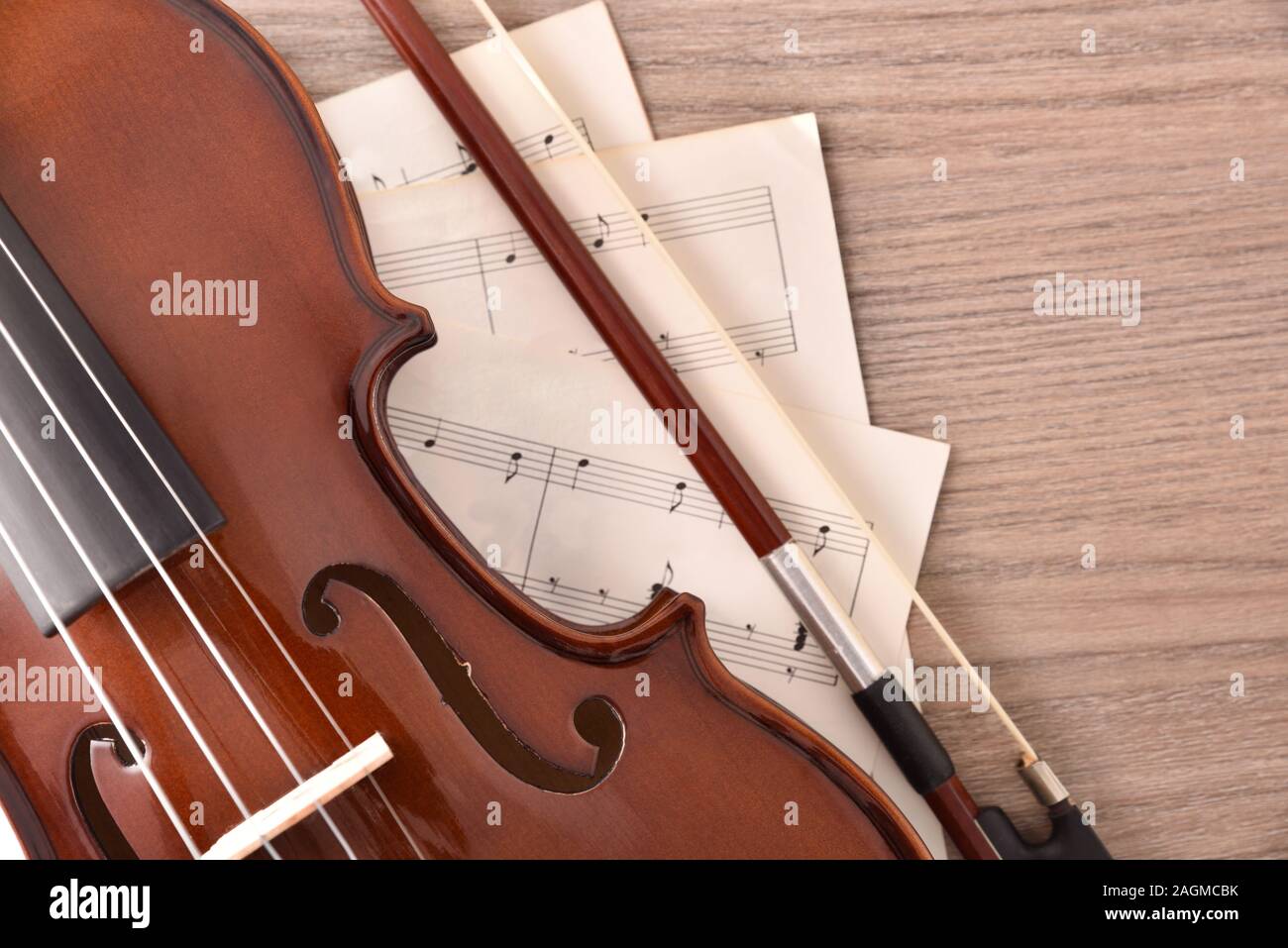 Violin body and bow with sheet music on wood table. Top view ...
