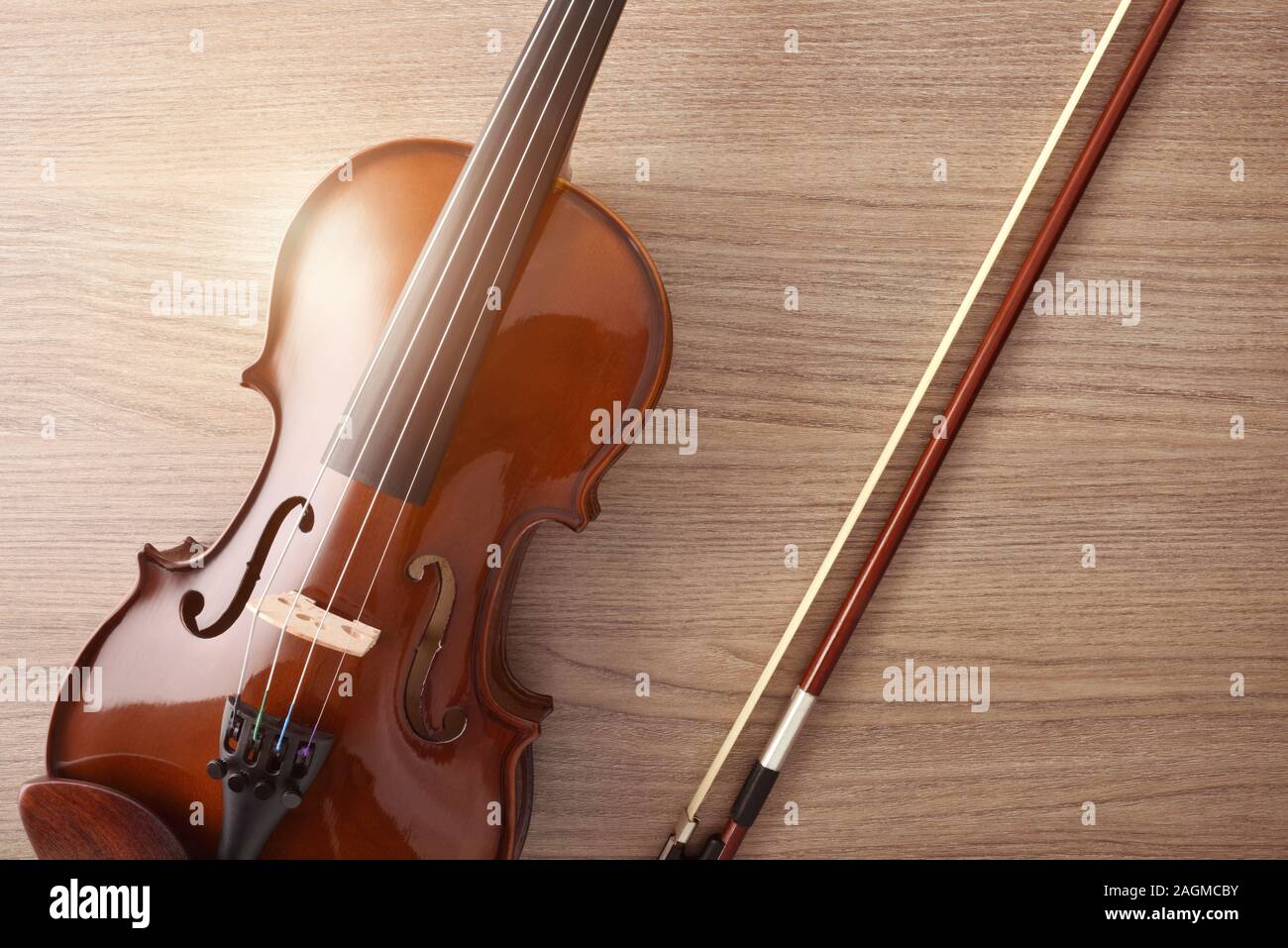 Violin body and bow on wood table with golden glow. Top view ...