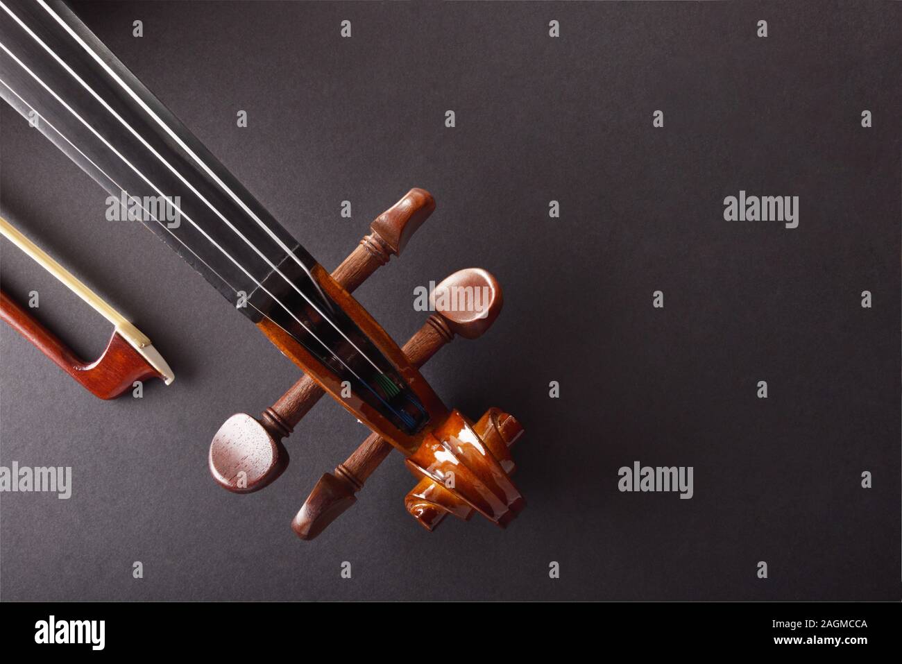 Violin pegbox and bow on black textured table Top view. Horizontal ...