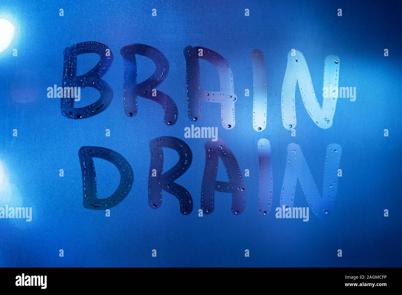 the words brain drain written on night wet window glass close-up with ...