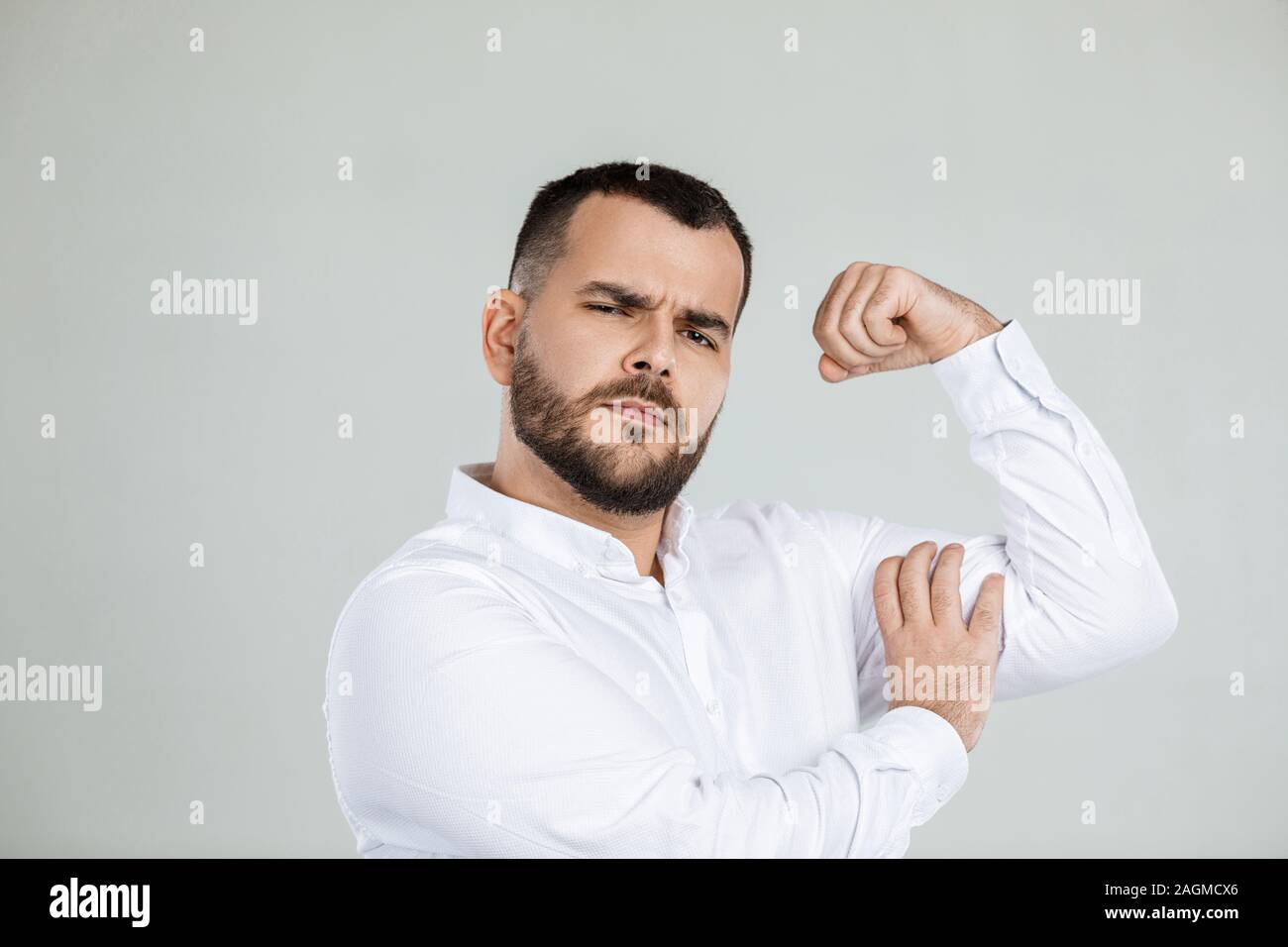 bearded muscular man shows biceps on gray background Stock Photo - Alamy
