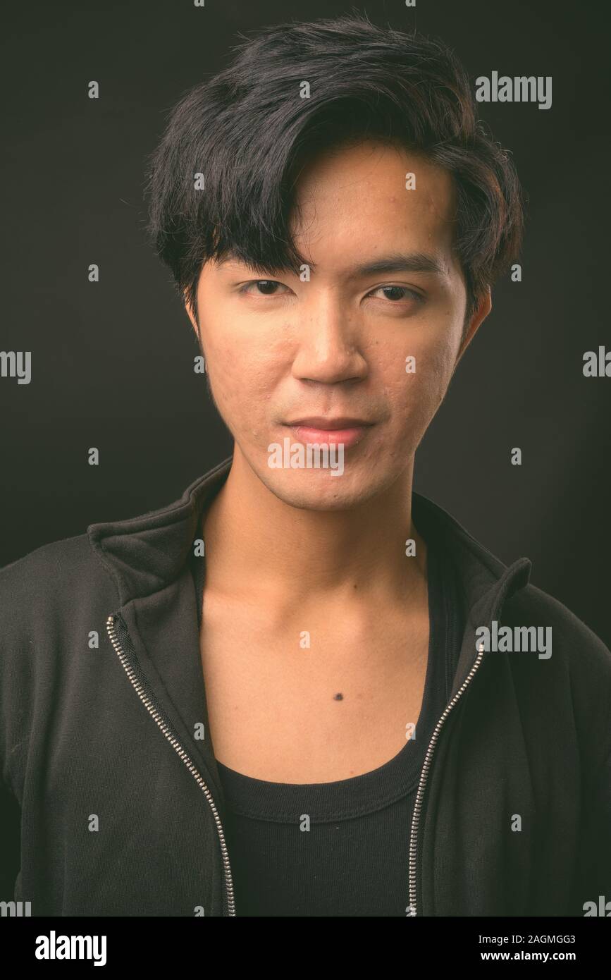 Young handsome Asian man against black background Stock Photo - Alamy