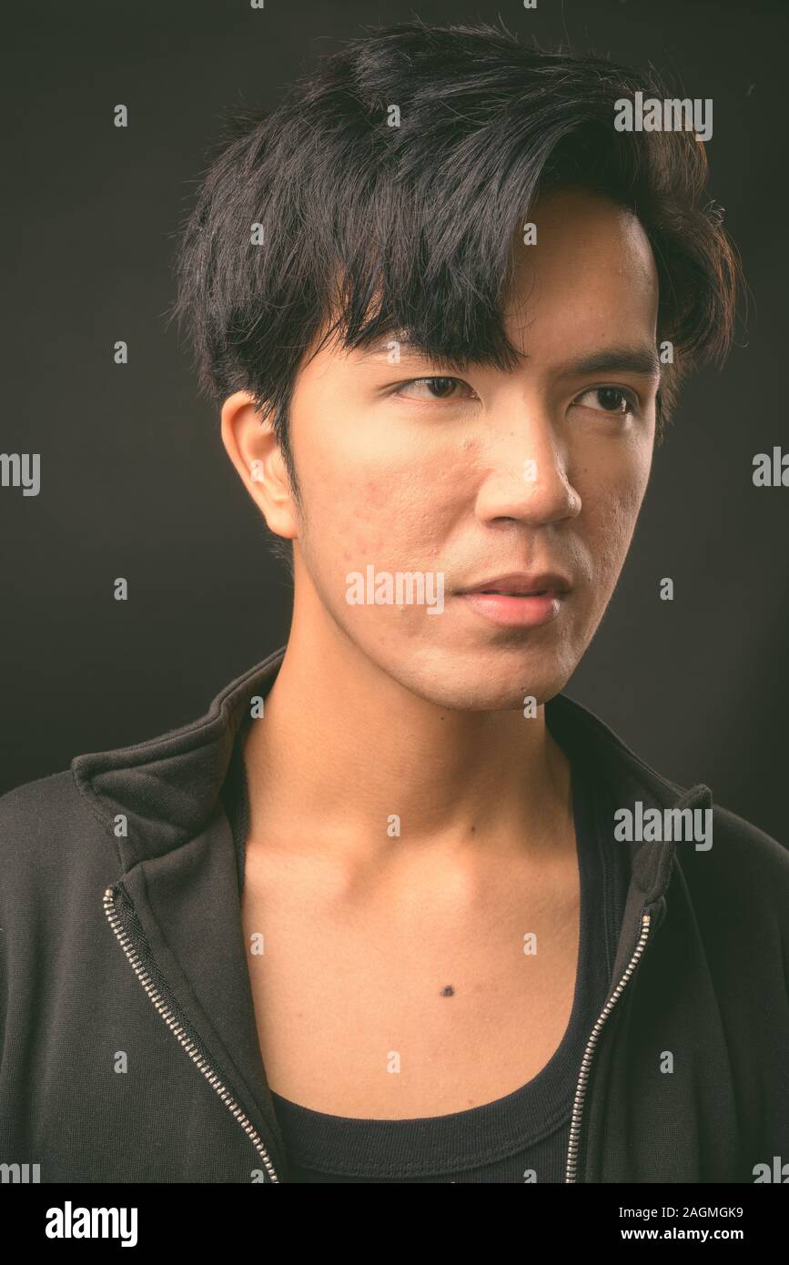 Young handsome Asian man against black background Stock Photo - Alamy