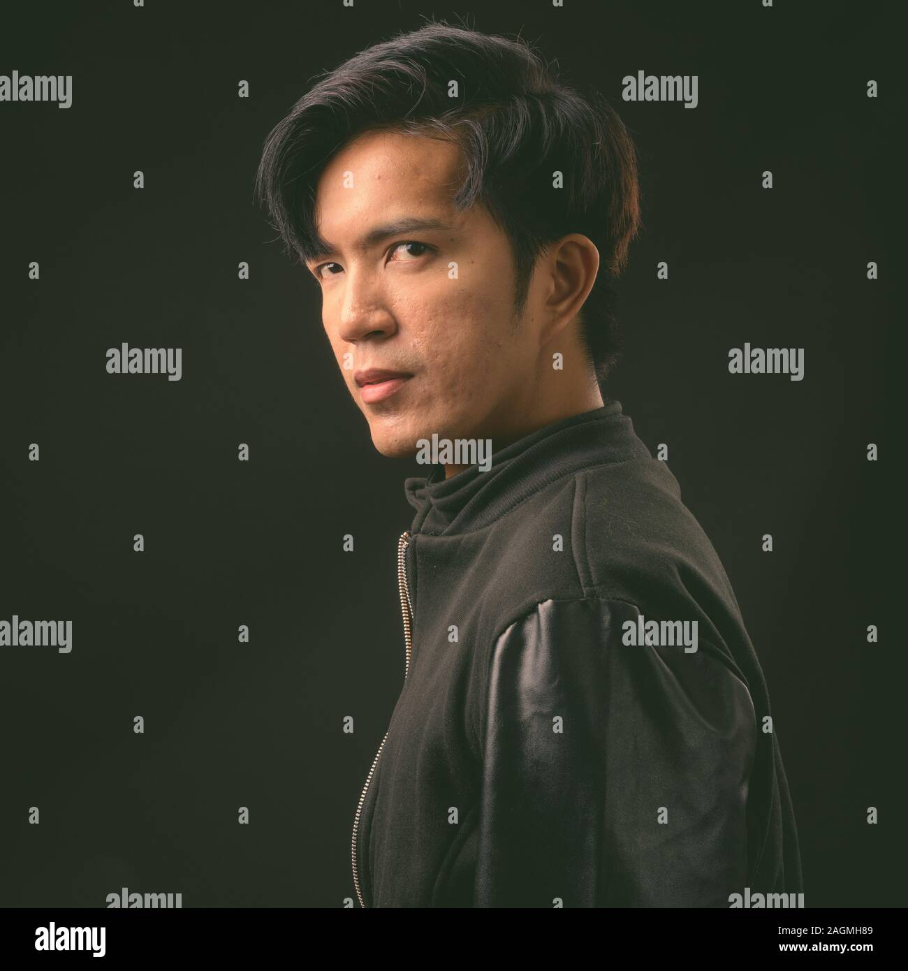 Young handsome Asian man against black background Stock Photo - Alamy