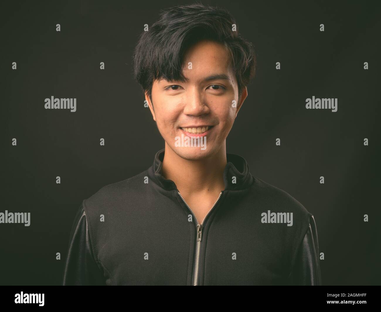 Young handsome Asian man against black background Stock Photo - Alamy