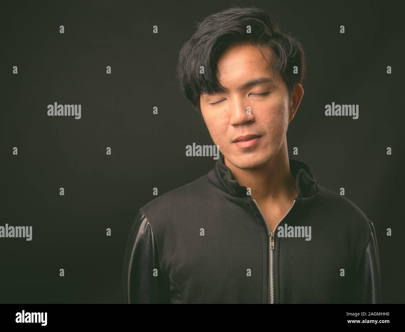 Young handsome Asian man against black background Stock Photo - Alamy