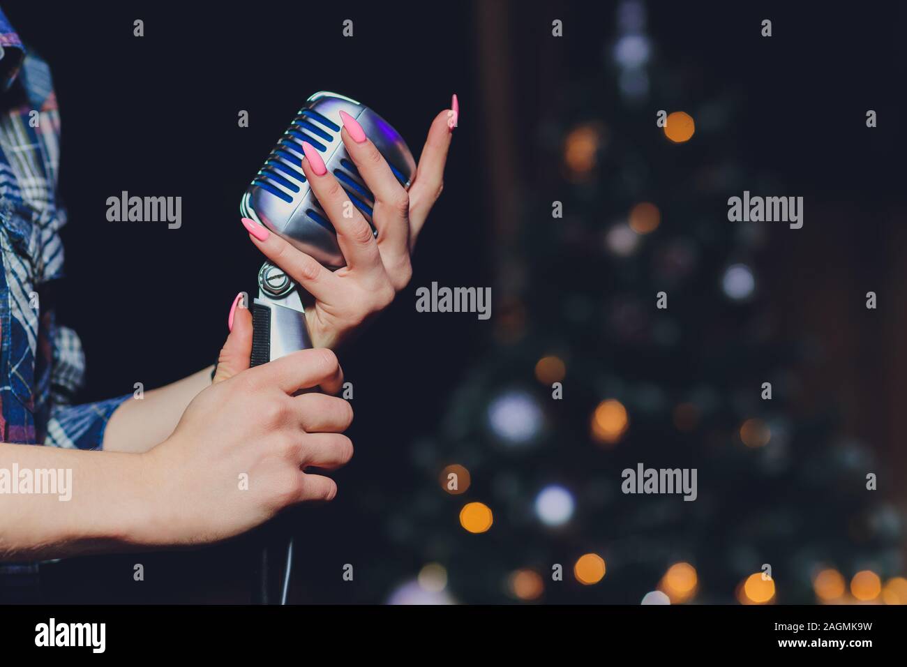 Female hand holding a single retro microphone against colourful ...