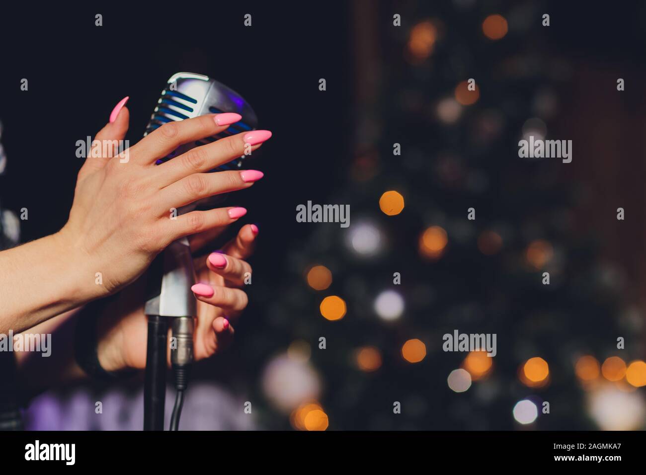 Female hand holding a single retro microphone against colourful ...