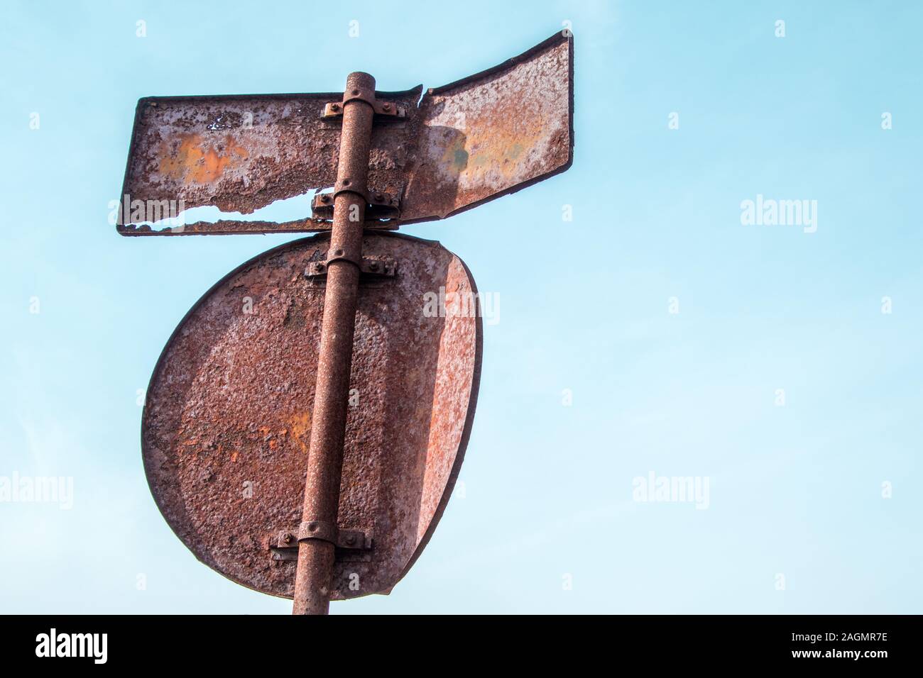 Two very old, rusted and weathered signs on a pole, against a blue sky ...
