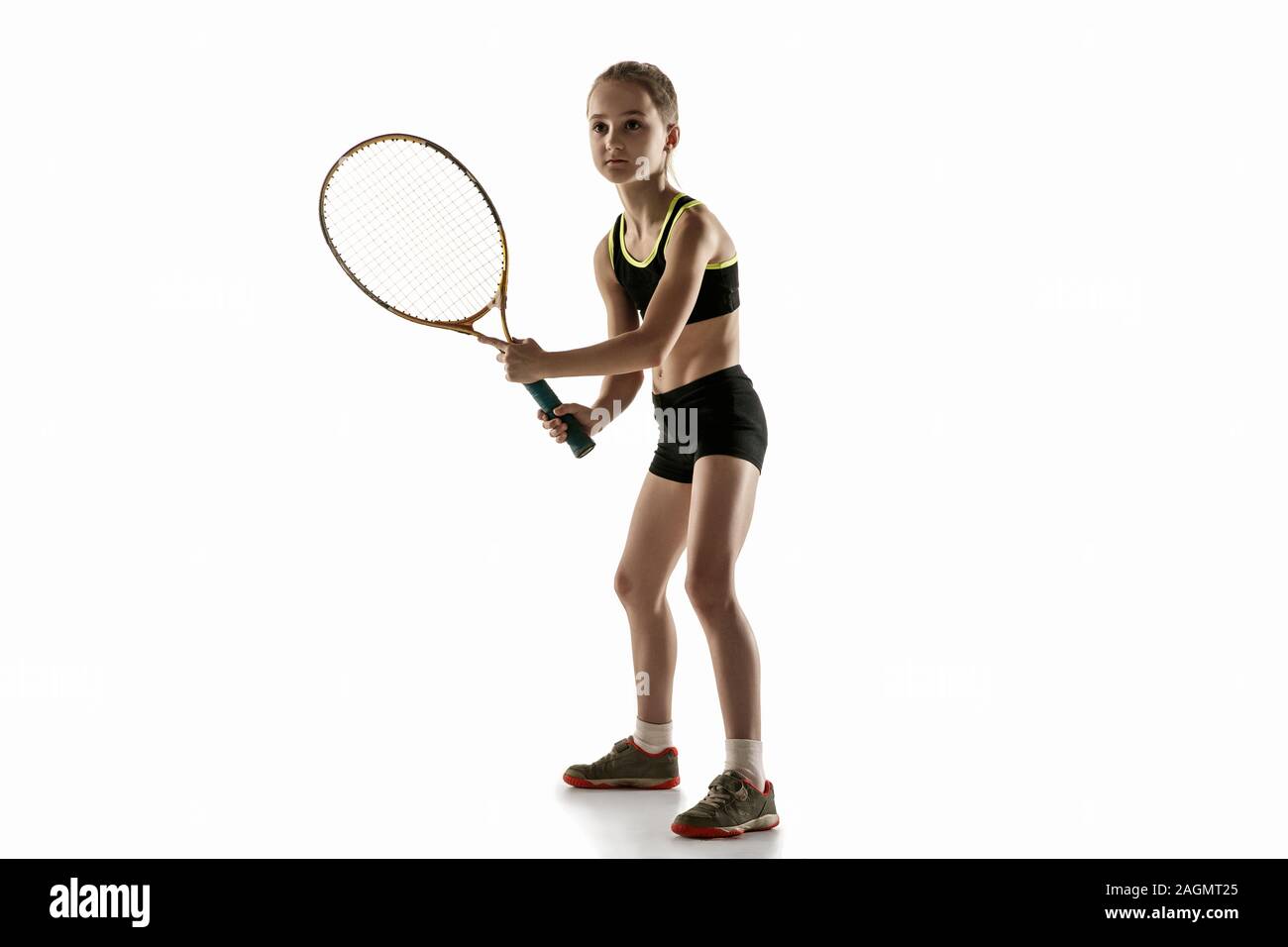Little caucasian girl playing tennis on white studio background. Cute ...