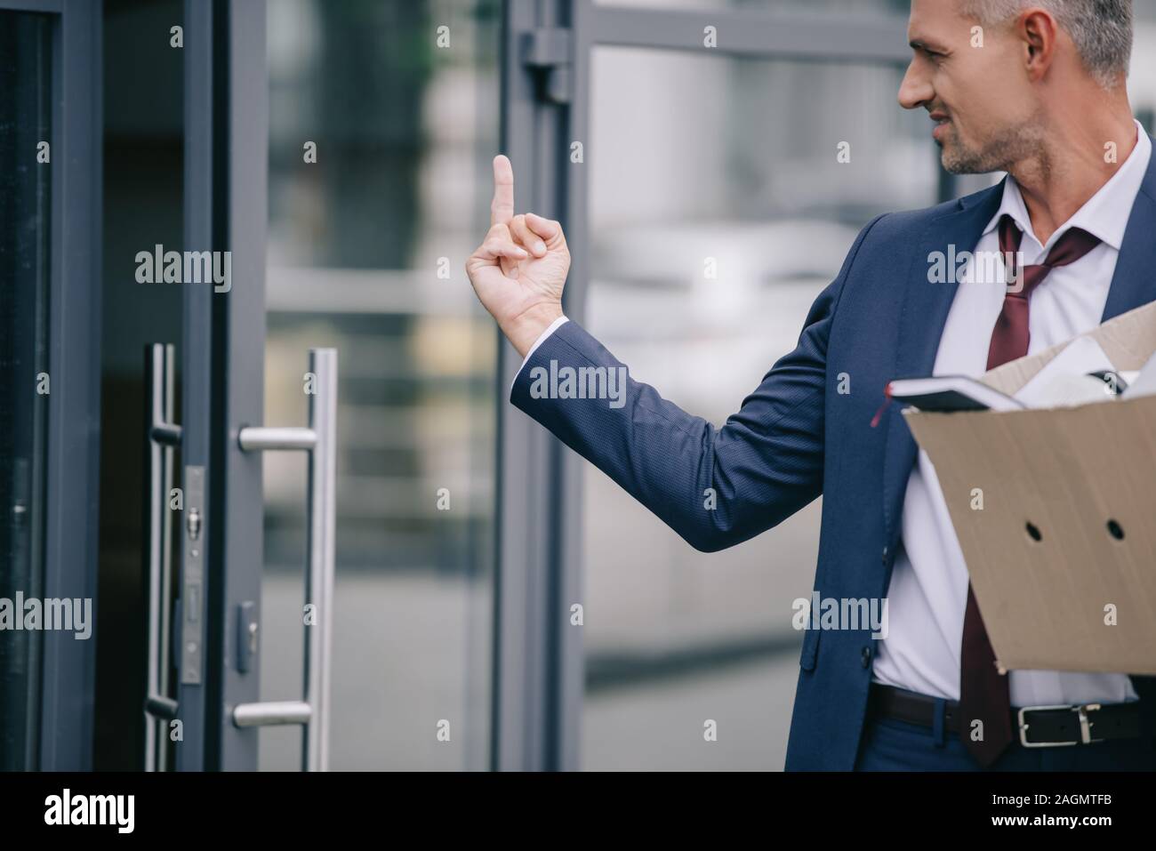 handsome man in suit showing middle finger while looking at door Stock ...