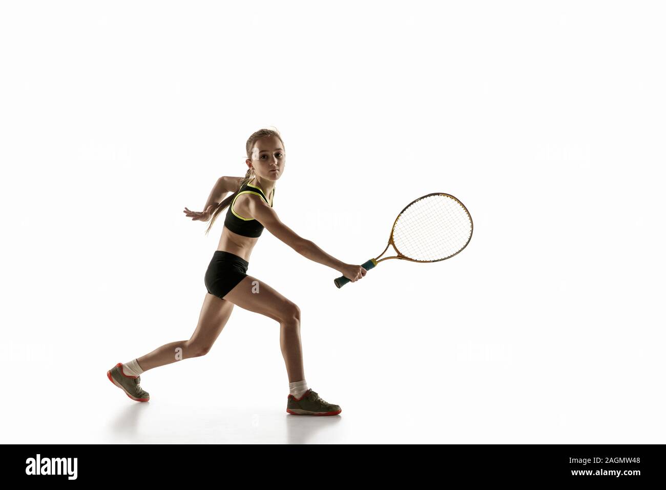 Little caucasian girl playing tennis on white studio background. Cute ...