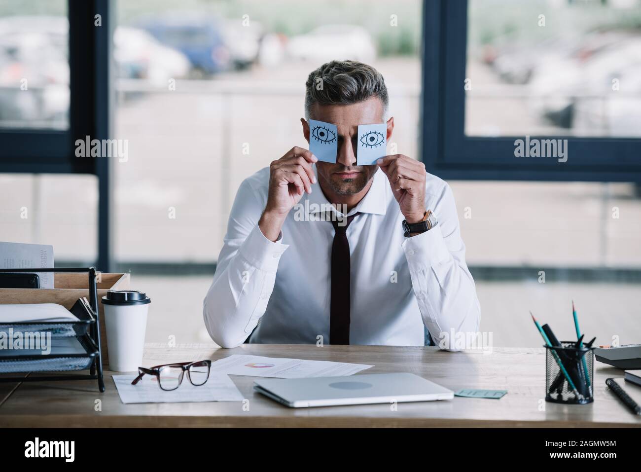 businessman holding sticky notes with drawn eyes near face Stock Photo ...