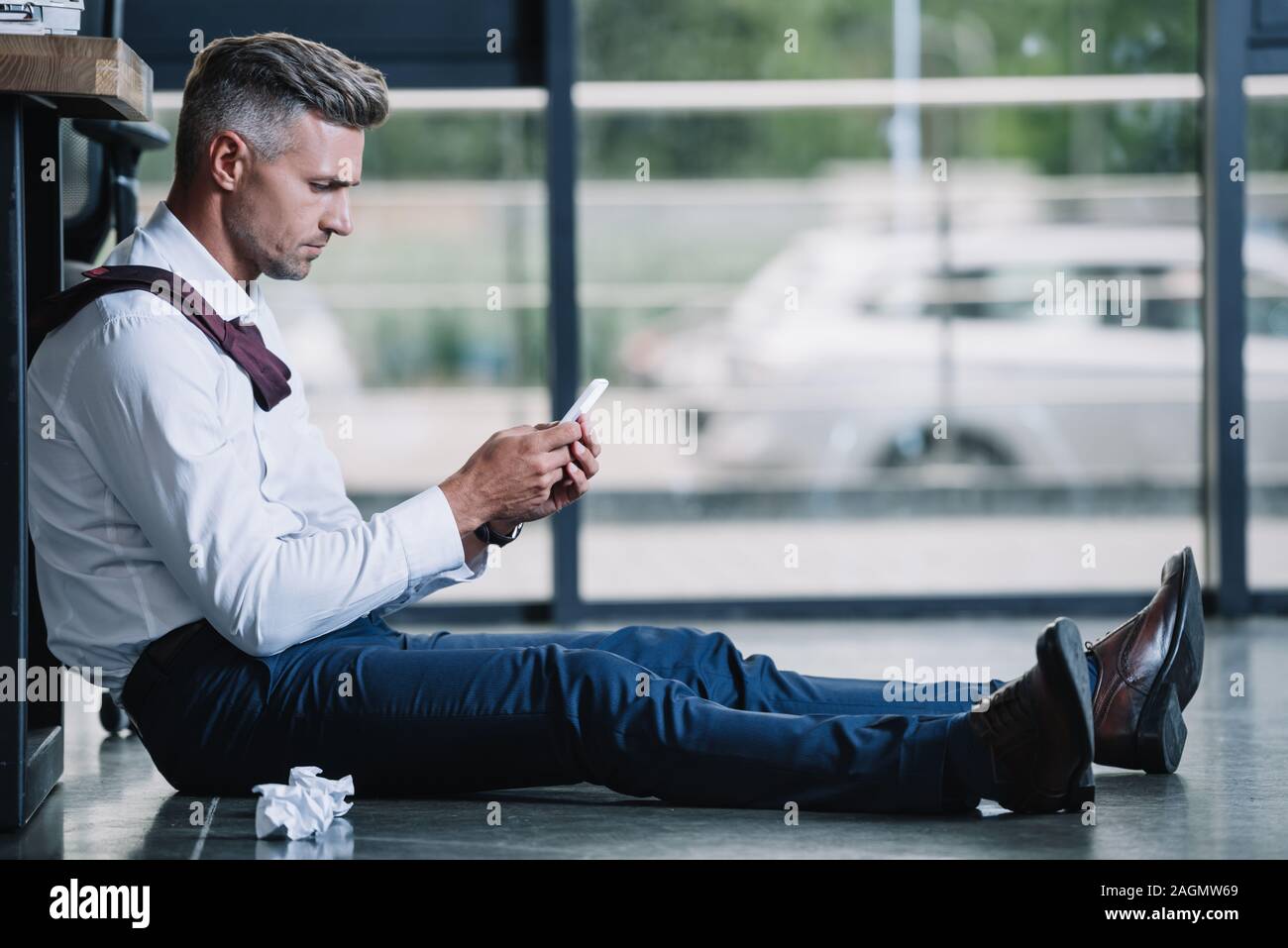 side view of businessman sitting on floor and using smartphone Stock ...