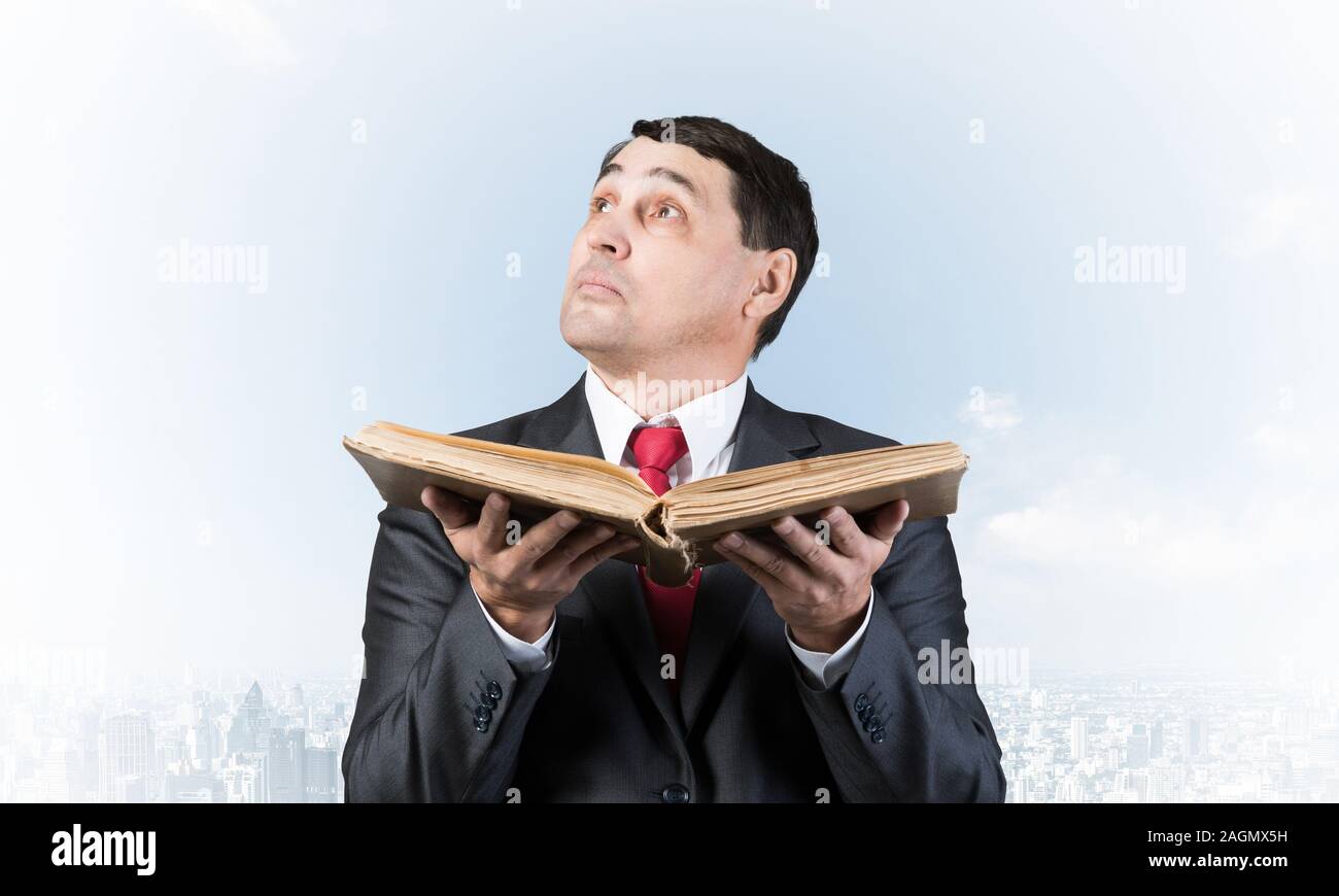 Serious businessman with open book looking up Stock Photo - Alamy