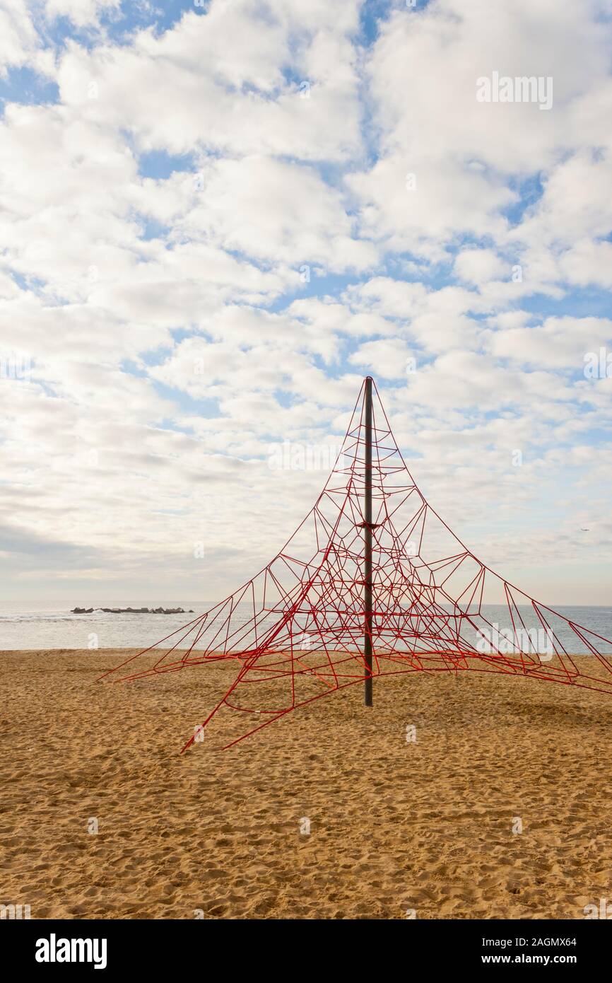 Empty red rope pyramid playground for climbing. Nobody in the beach and ...