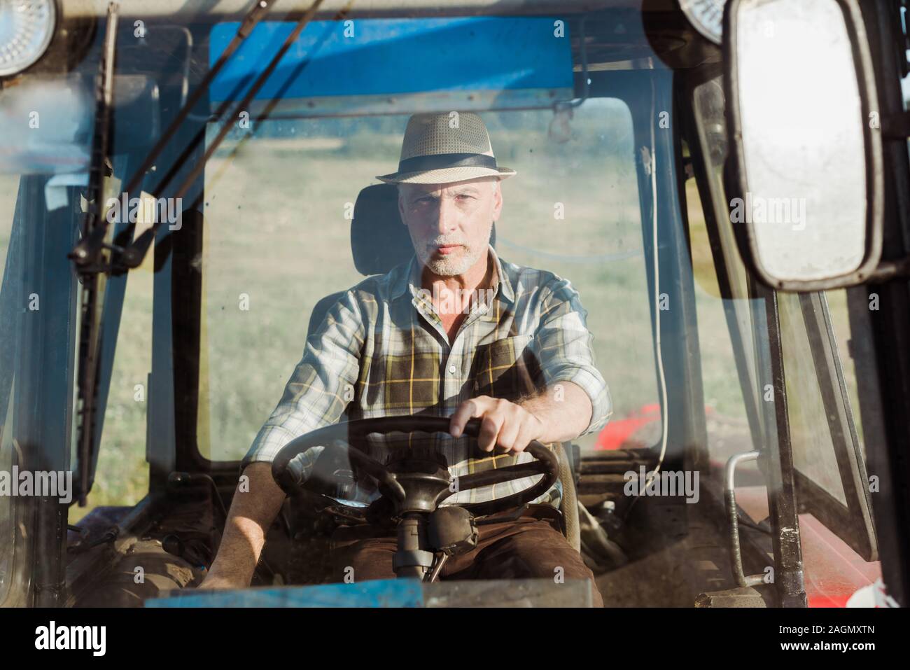 selective focus of senior self-employed man driving tractor Stock Photo ...