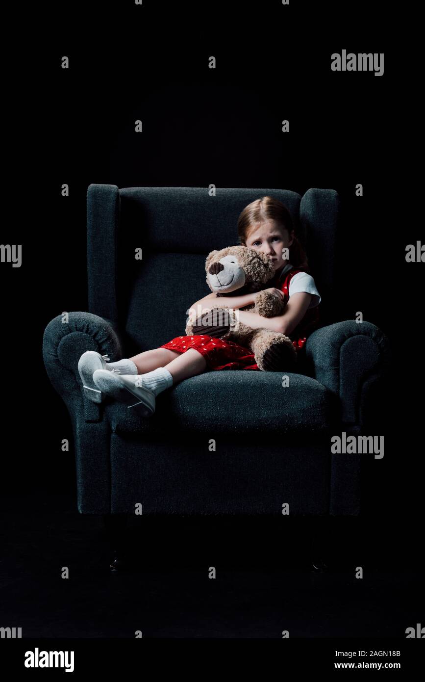 depressed, scared child sitting in armchair and hugging teddy bear ...