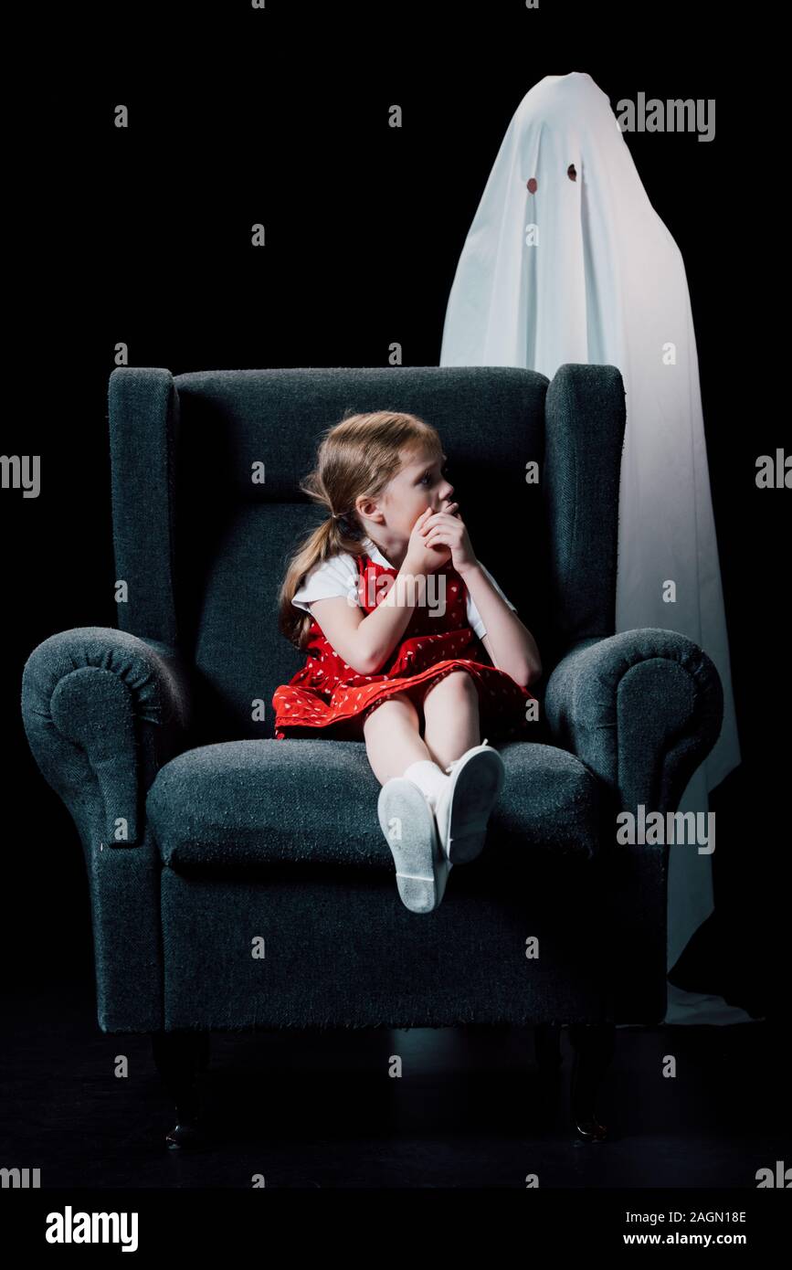 frightened child showing hush sign near white ghost standing behind ...