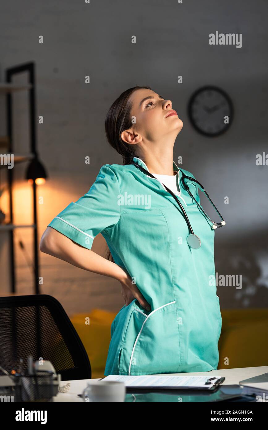 attractive nurse in uniform having back pain during night shift Stock ...