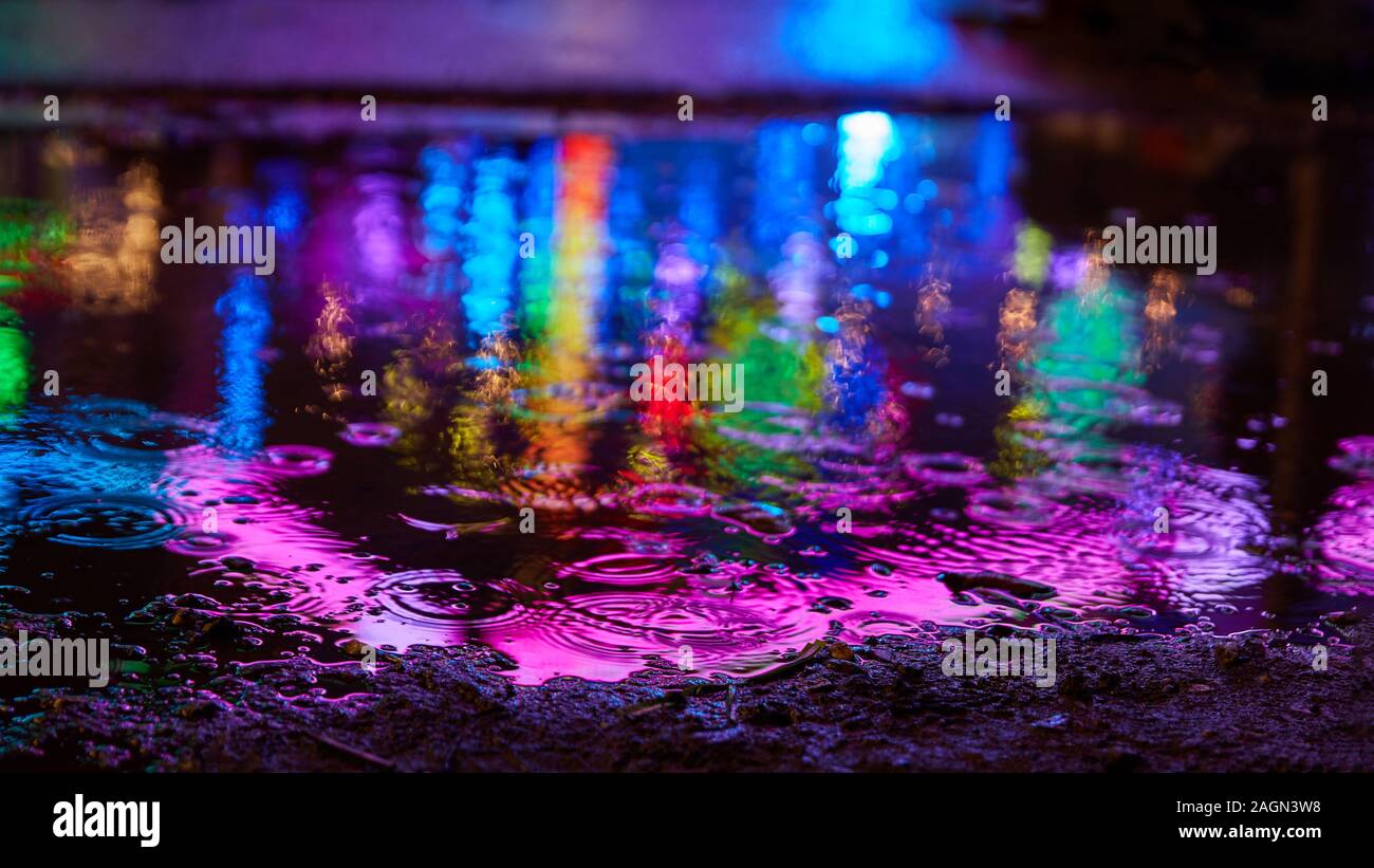 Reflection of colorful lights from the fair in a puddle when it rains ...