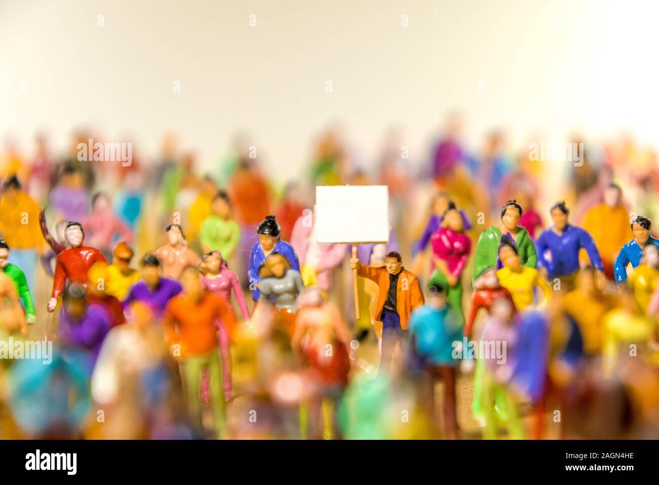 A large crowd of plastic figure people stand in a protest, in the ...