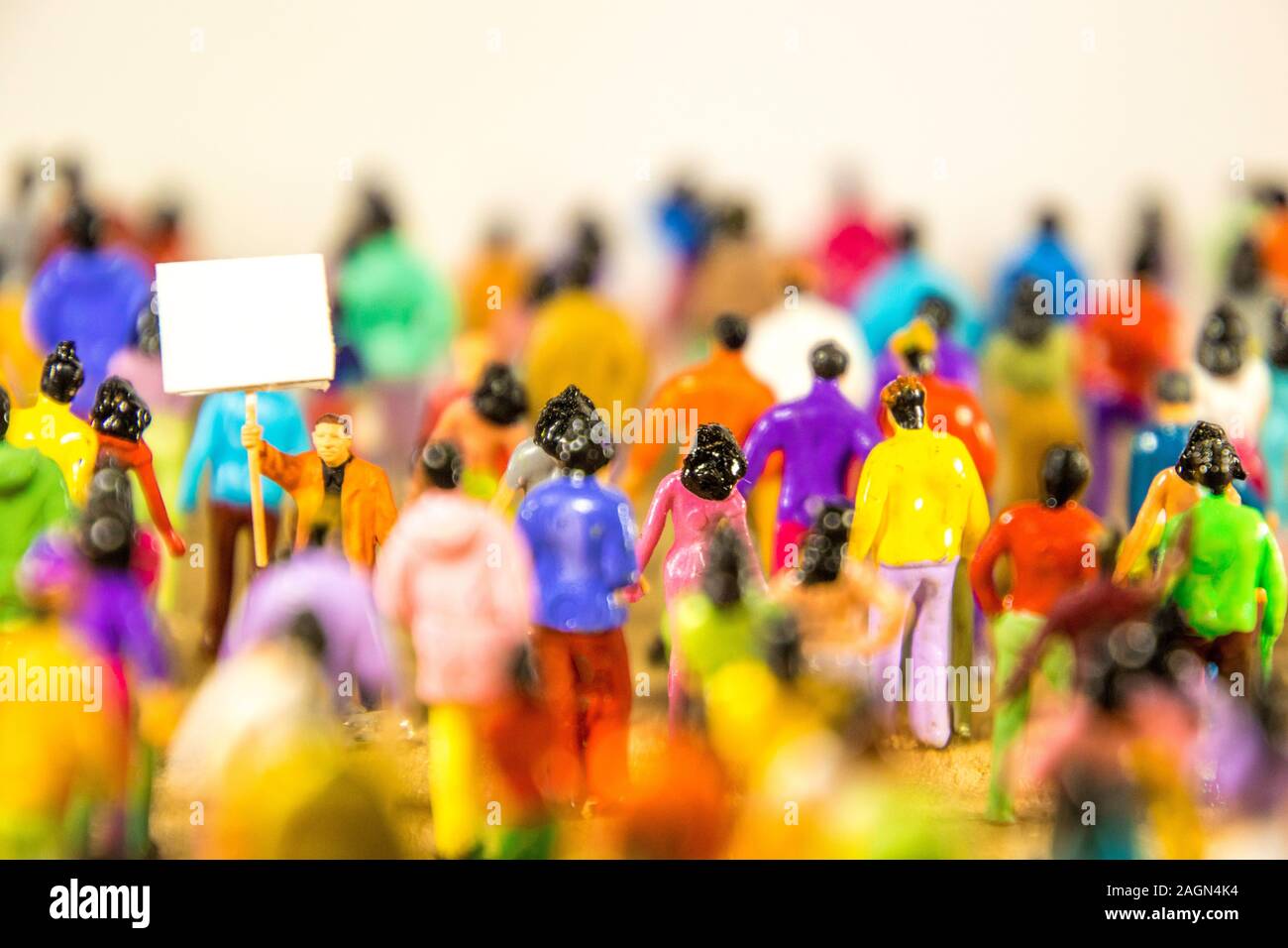 A large crowd of plastic figure people stand in a protest, in the ...