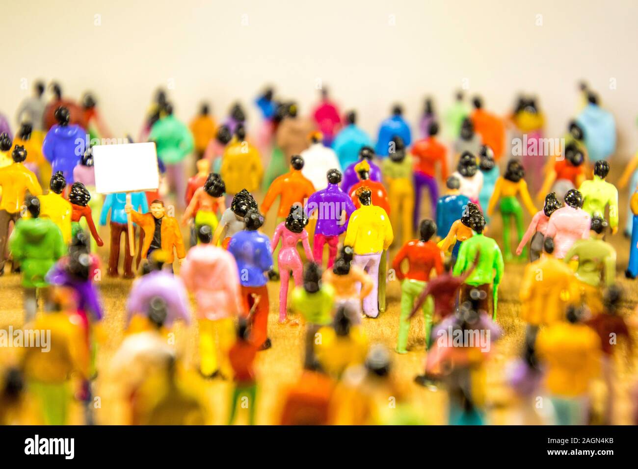 A large crowd of plastic figure people stand in a protest, in the ...