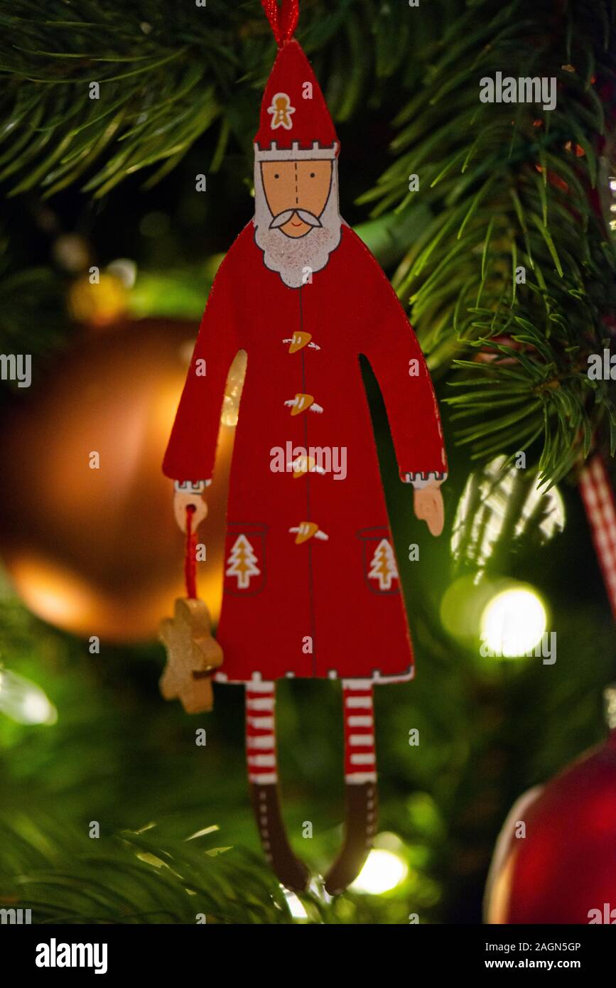 A wooden Father Christmas decoration hanging in an artificial Christmas ...