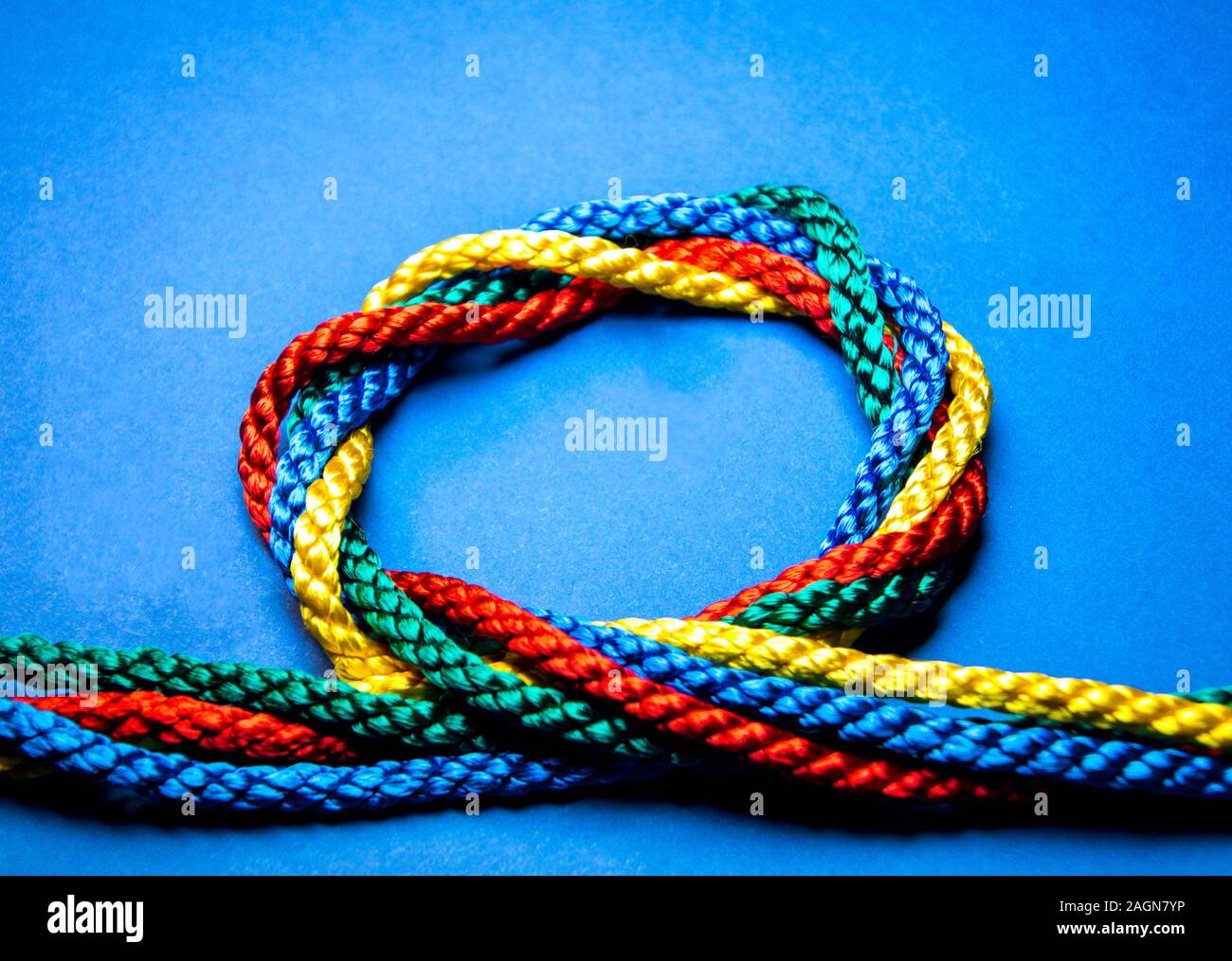 Colourful primary coloured string twisted on a bright blue background ...