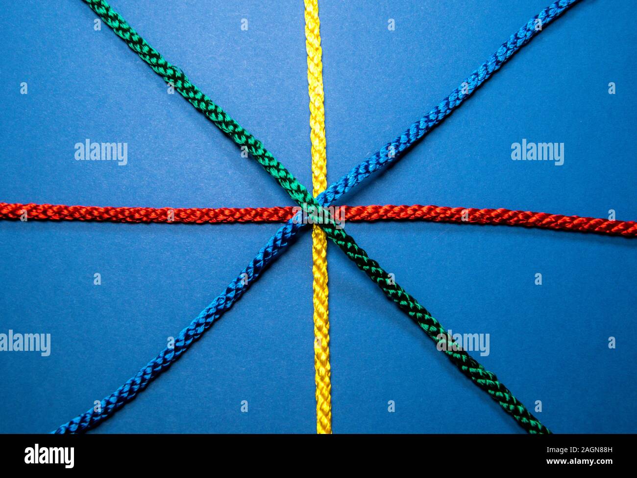 Colourful primary coloured string twisted on a bright blue background ...
