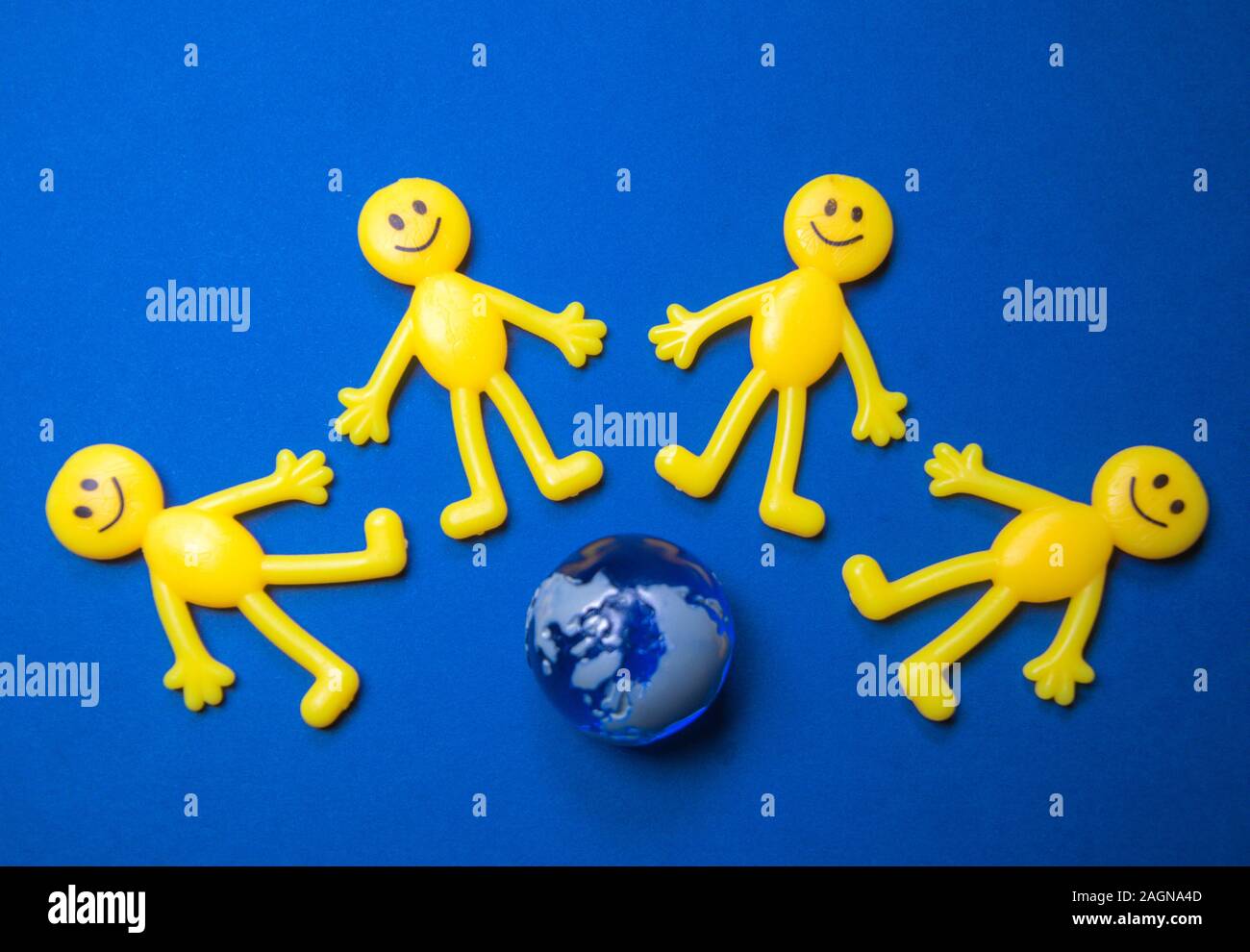 Yellow figure people surround the top of a miniature version of planet ...