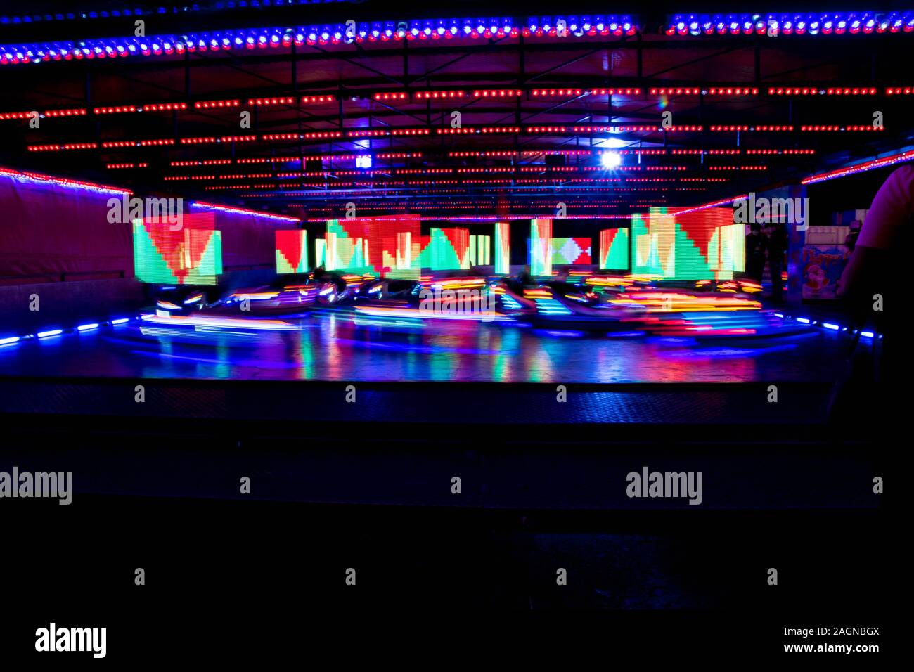 Lights dash around from several Dodgem cars as people have fun bumping ...