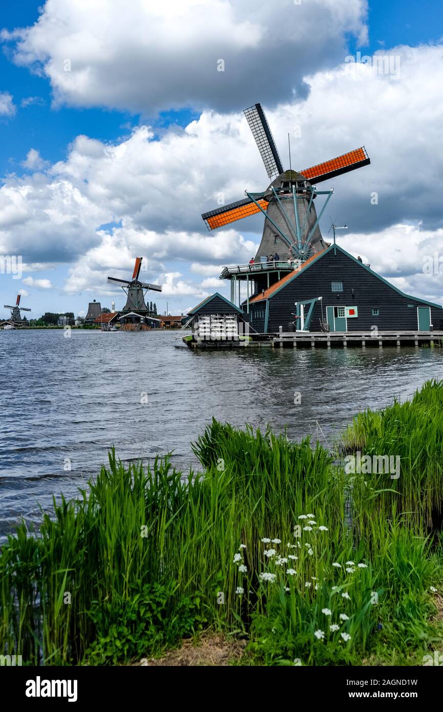 Vertical shot of a country scenery with a windmill at the river shore ...