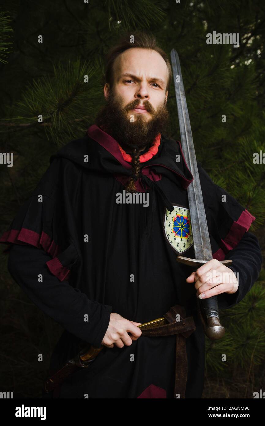 Knight in tunic with sword on shoulder Stock Photo - Alamy