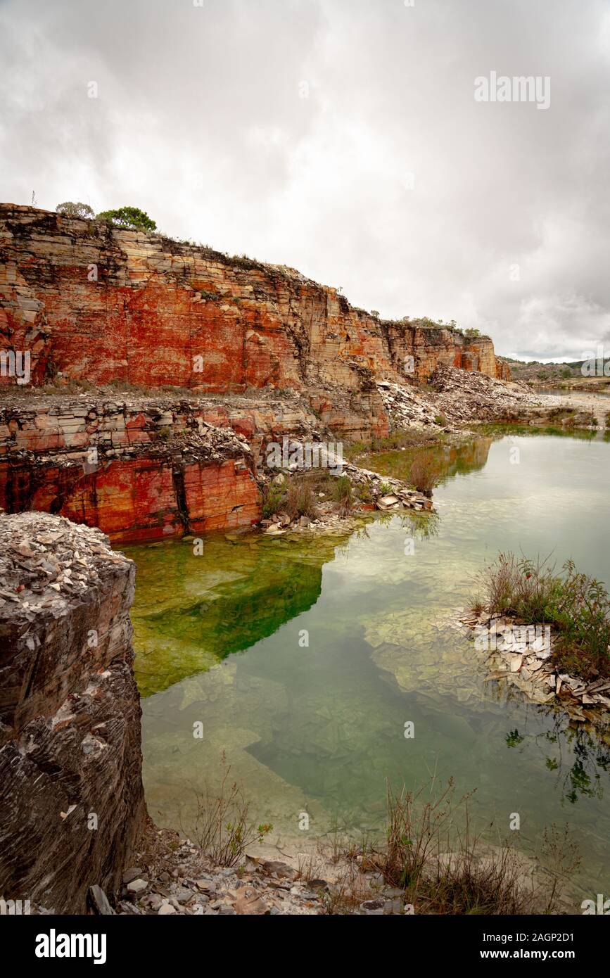 An old quarry with red layers of rocks and green water in Minas Gerais ...